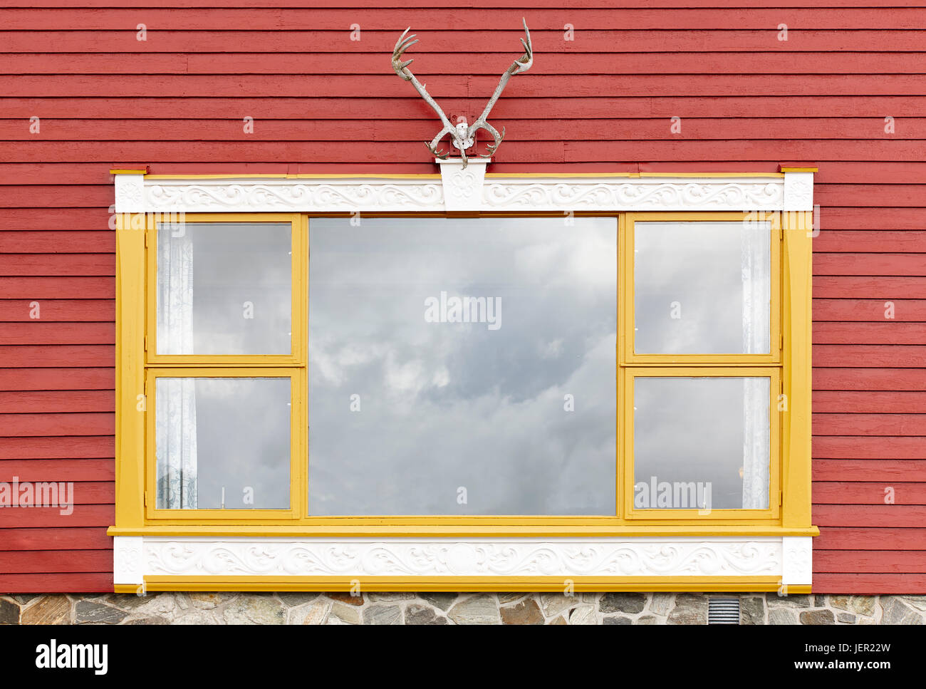 Red wooden facade with yellow window and deer horn. Horizontal Stock ...