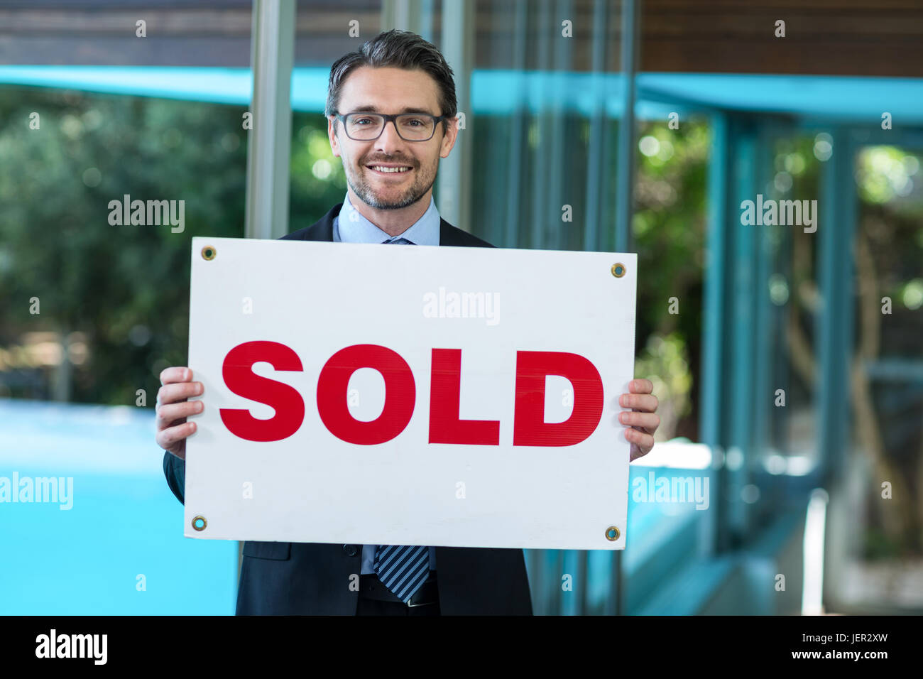 Real estate agent holding sold sign Stock Photo - Alamy