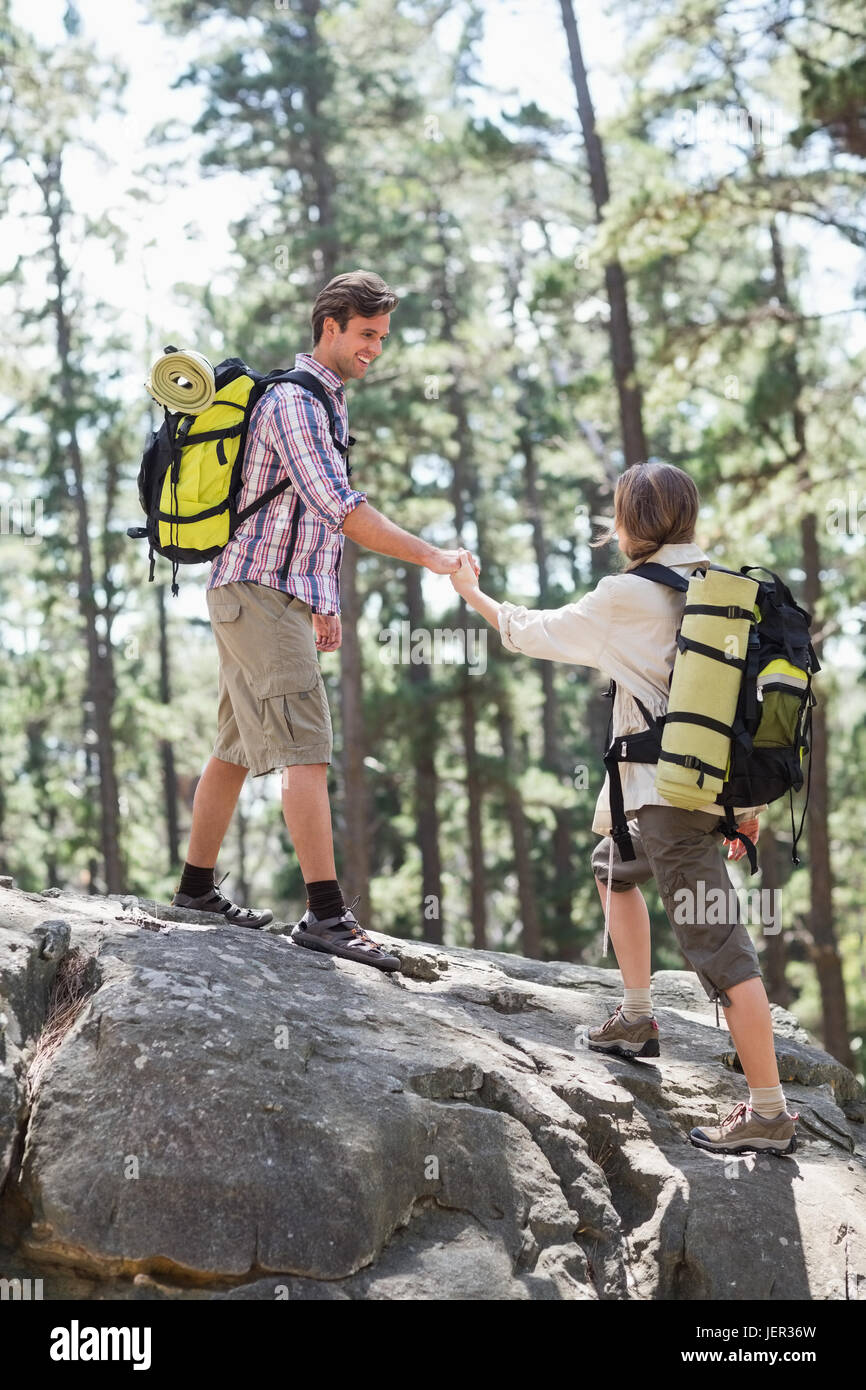 Man helping woman climb rock in forest Stock Photo - Alamy