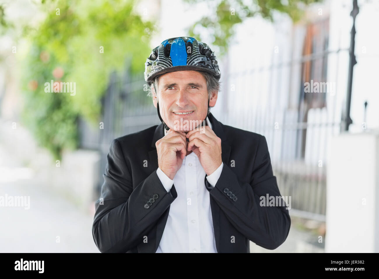 Front view of businessman adjusting helmet Stock Photo - Alamy