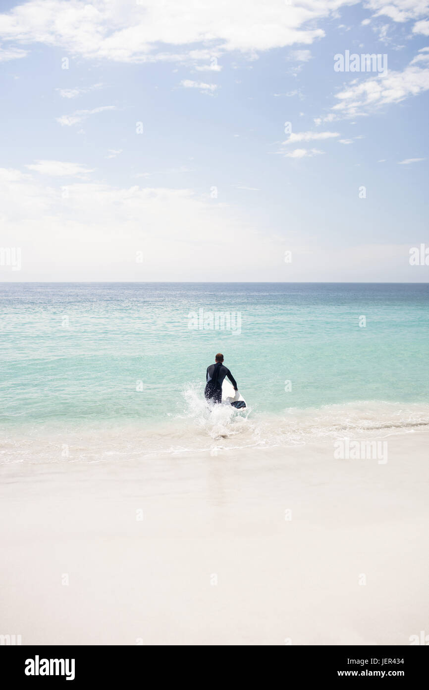 Surfer running towards sea with a surfboard Stock Photo - Alamy