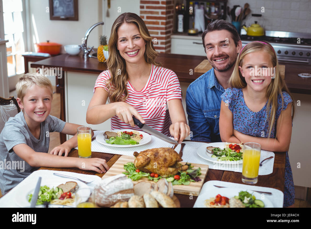 Smiling family sitting at dining table Stock Photo - Alamy