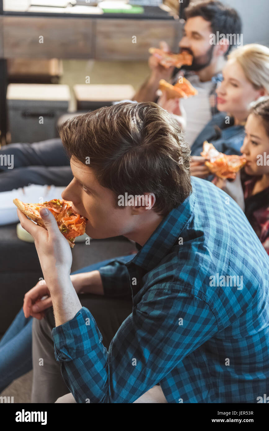 young people eating pizza while sitting on couch Stock Photo - Alamy
