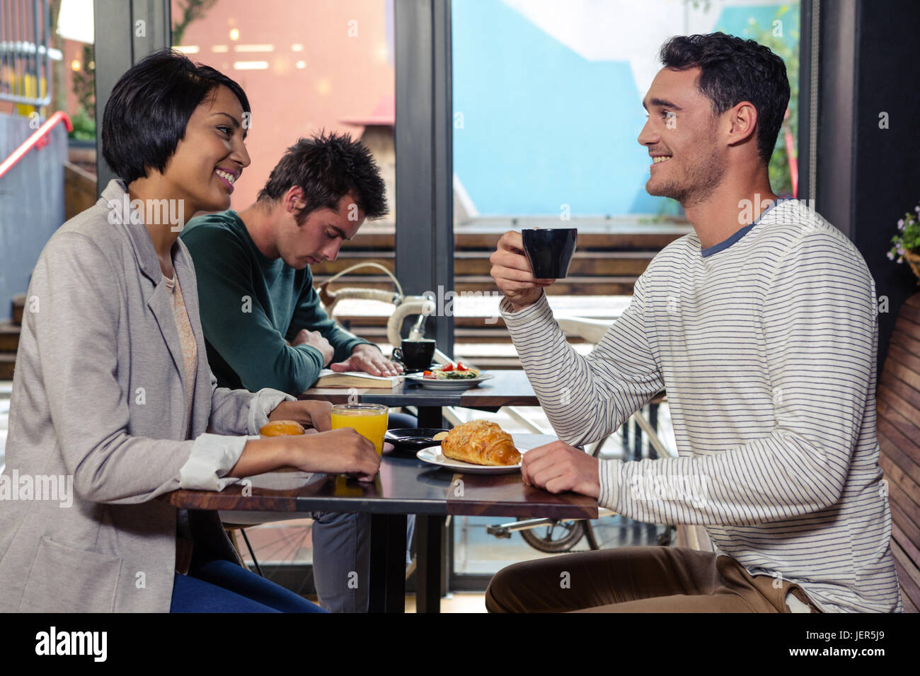 Cute couple talking while eating Stock Photo - Alamy