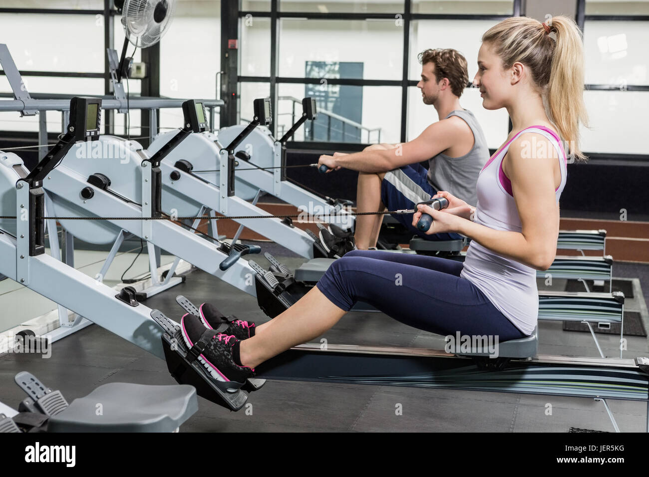 Man and woman working out on rowing machine Stock Photo - Alamy