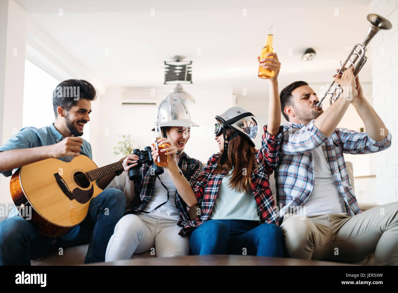 Cheerful young friends having party together and playing instruments ...