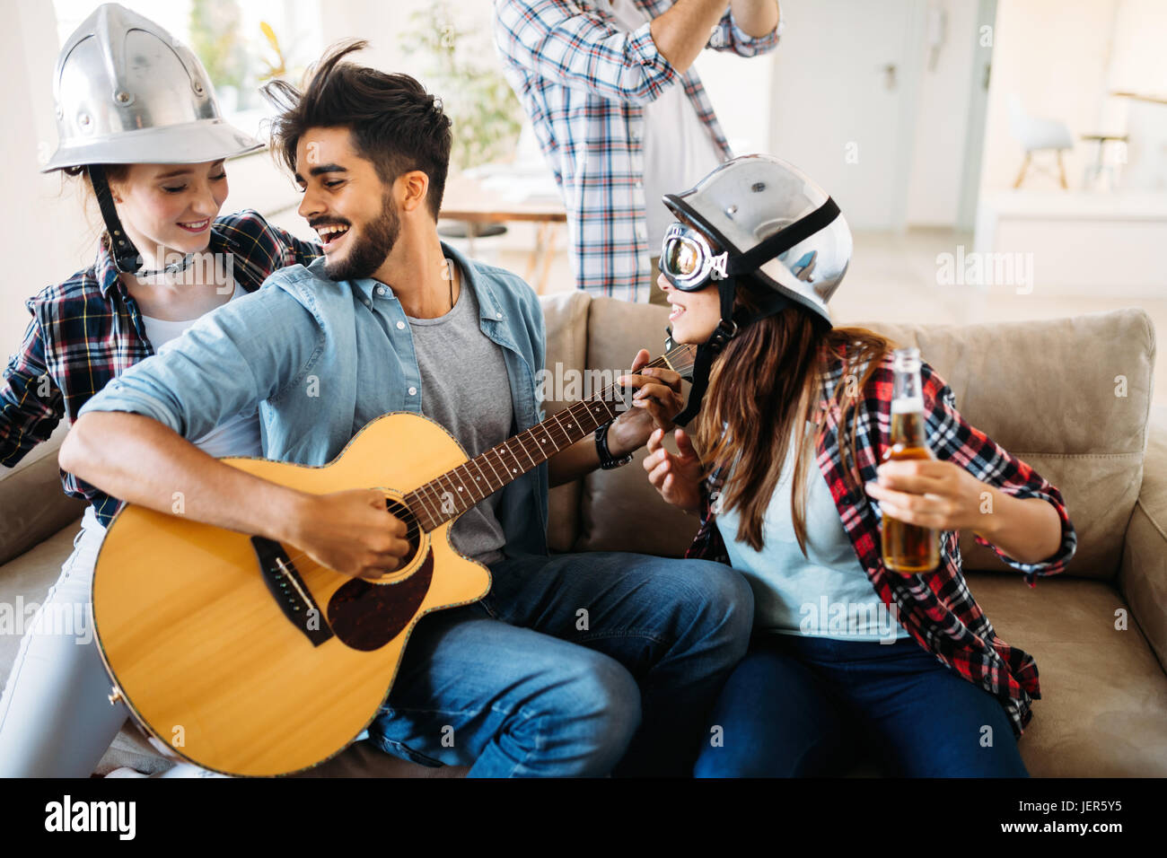 Cheerful young friends having party together and playing instruments ...
