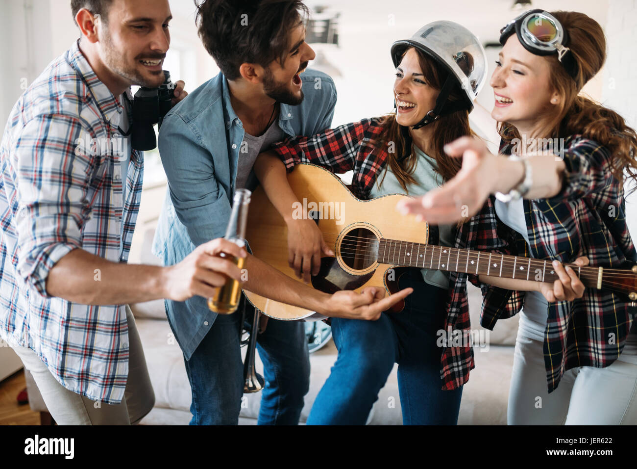 Cheerful young friends having party together and playing instruments ...