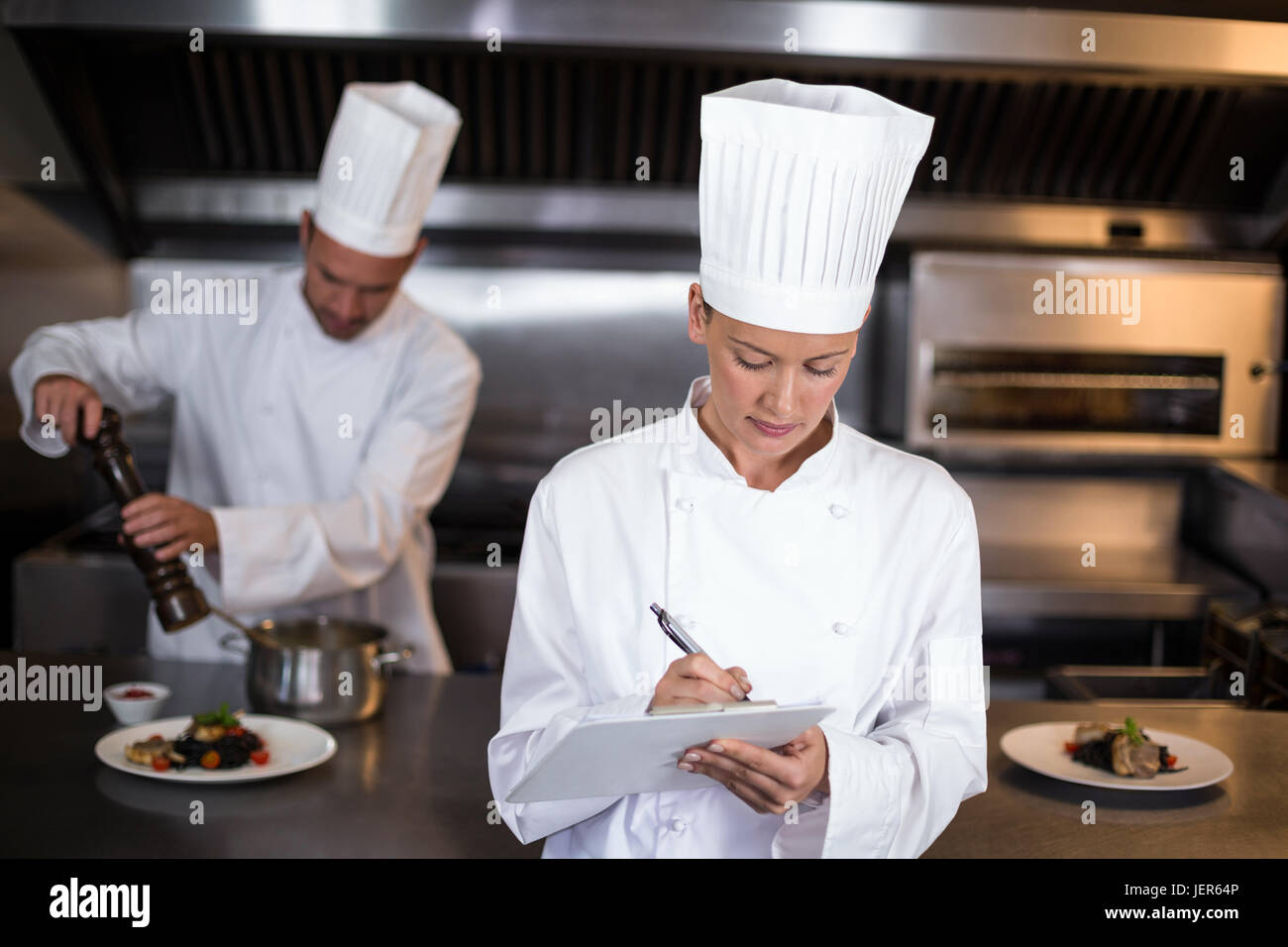 Female chef writing on clipboard Stock Photo - Alamy
