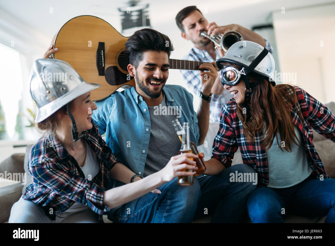 Cheerful young friends having party together and playing instruments ...