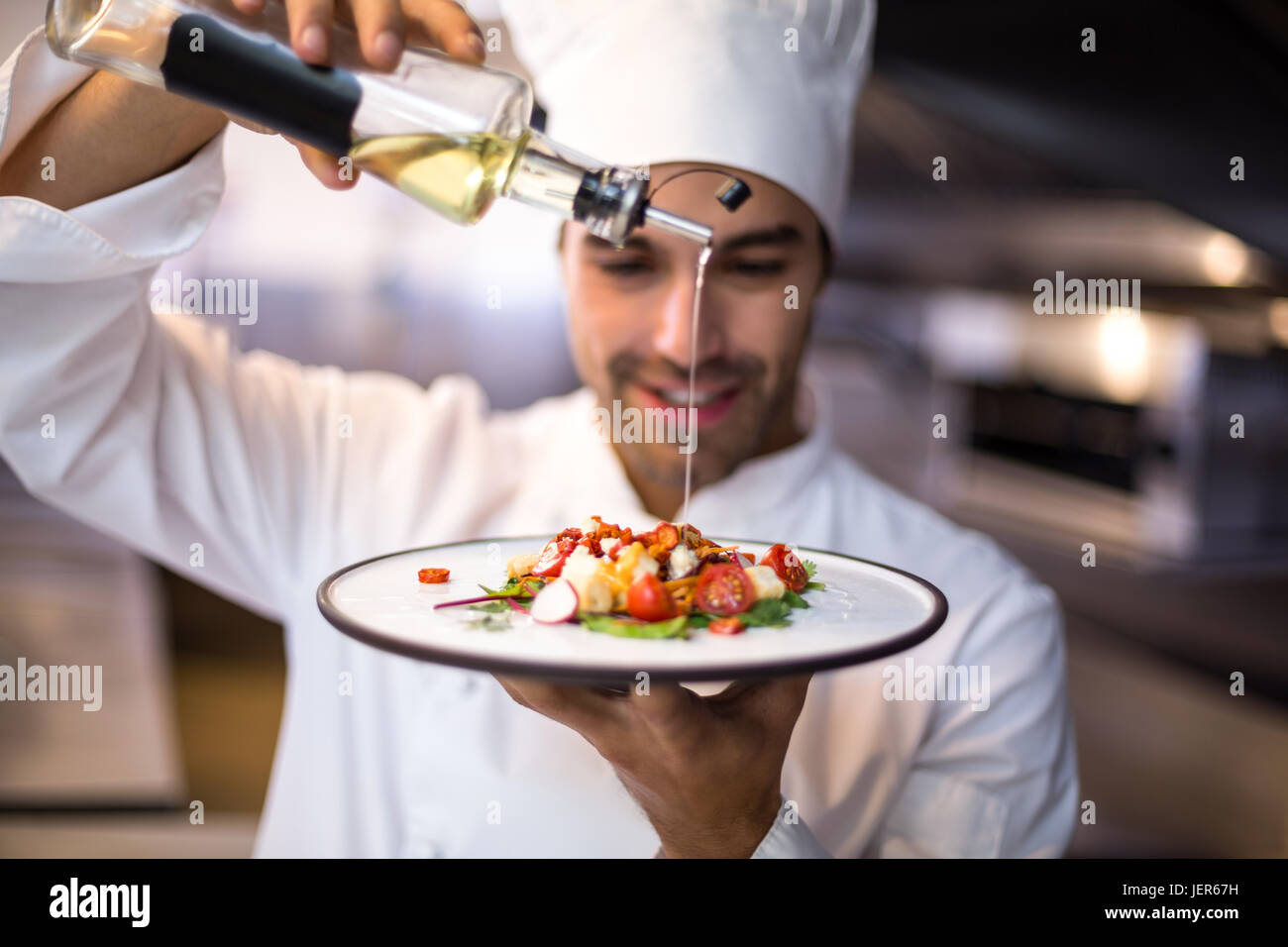 Handsome chef pouring olive oil on meal Stock Photo - Alamy