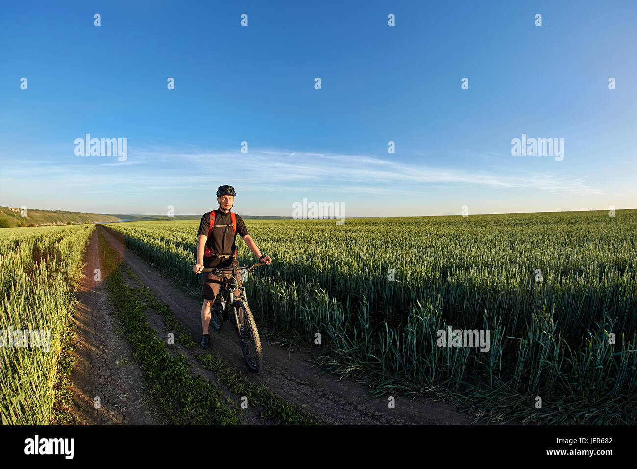 Attractive cyclist standing with bike and observing the view against ...