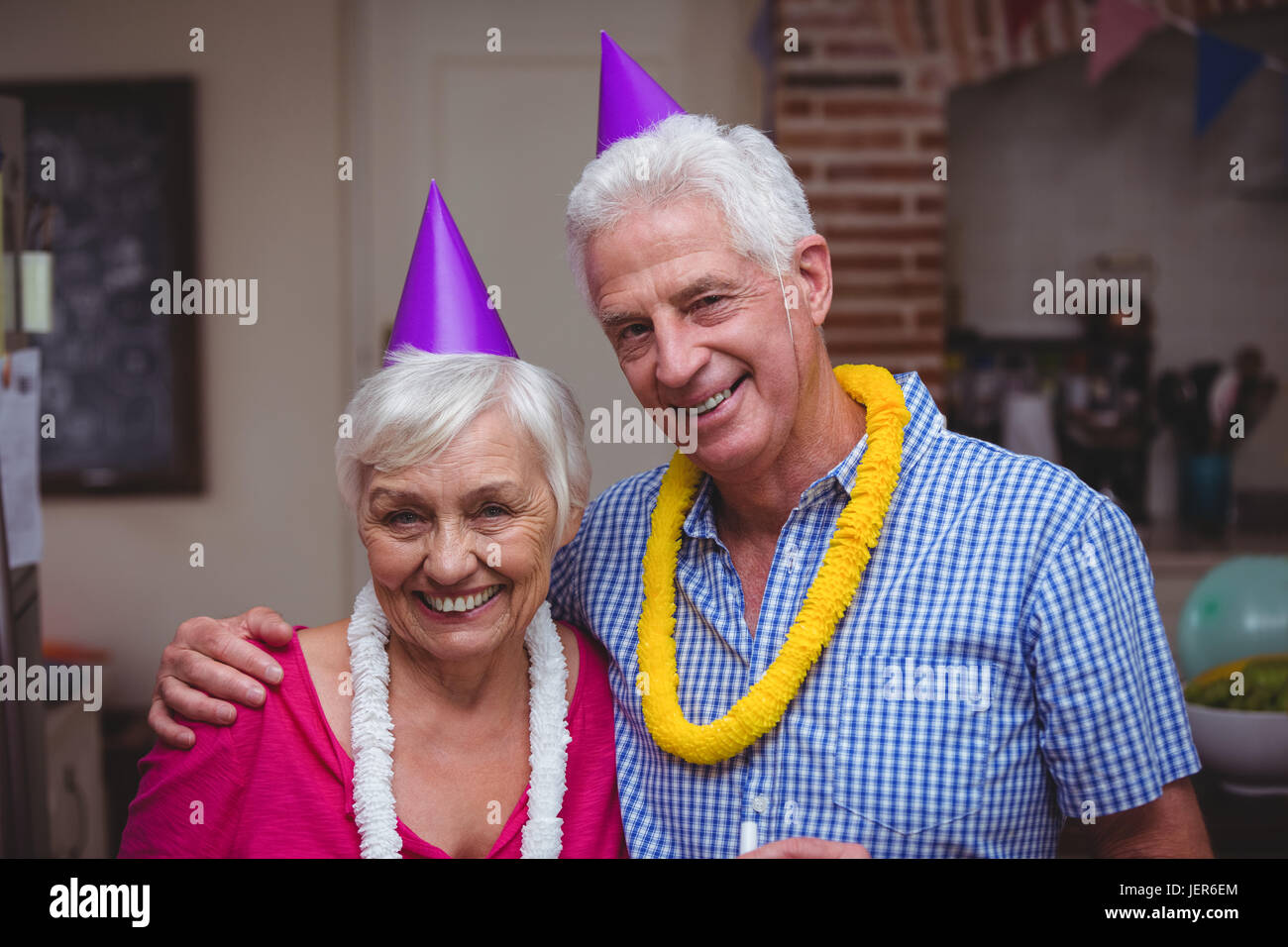 Smiling senior couple wearing party hat Stock Photo - Alamy