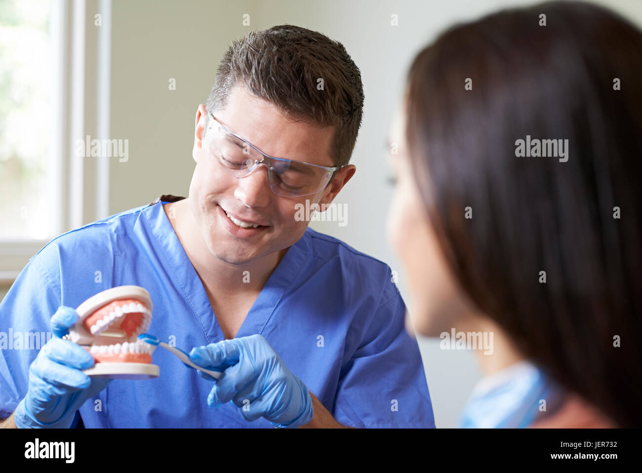 Dentist Demonstrating Correct Use Of Toothbrush To Female Client Stock ...
