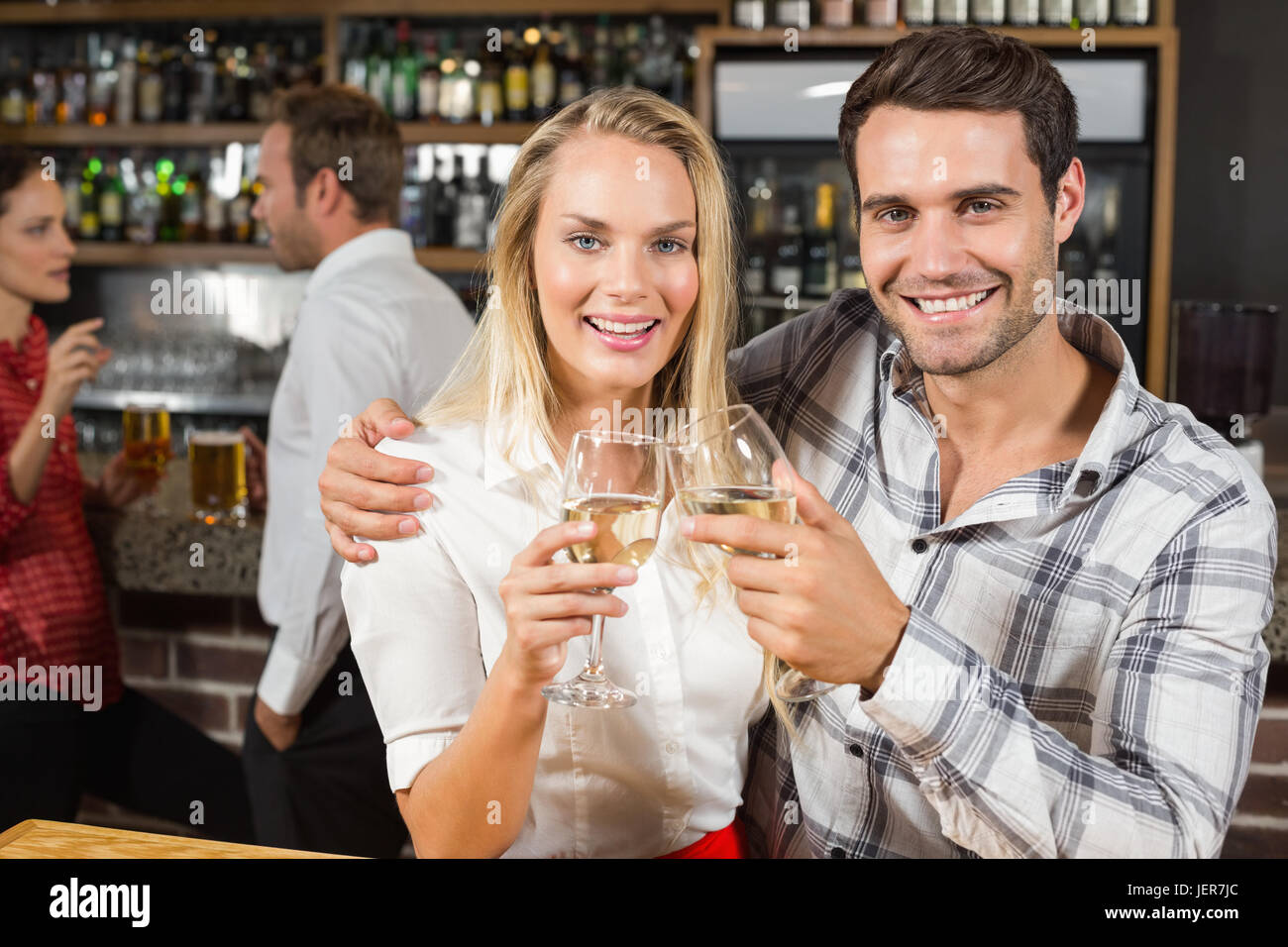 Couple smiling at camera and toasting Stock Photo - Alamy