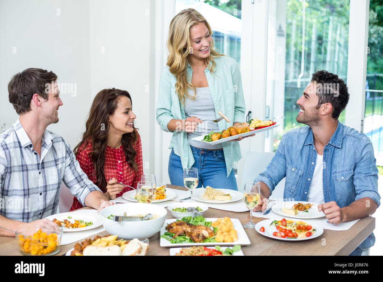Woman serving food to friends Stock Photo - Alamy