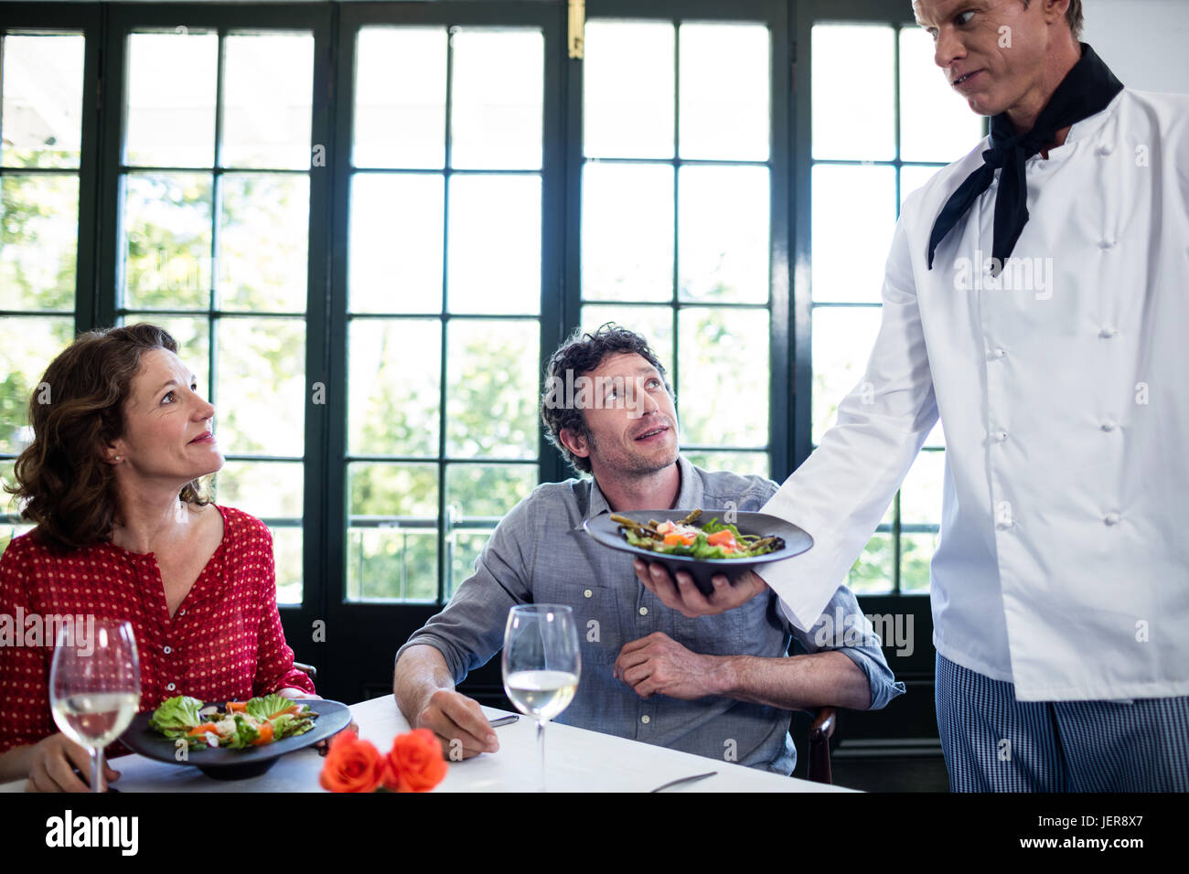 Chef serving meal to a couple Stock Photo - Alamy