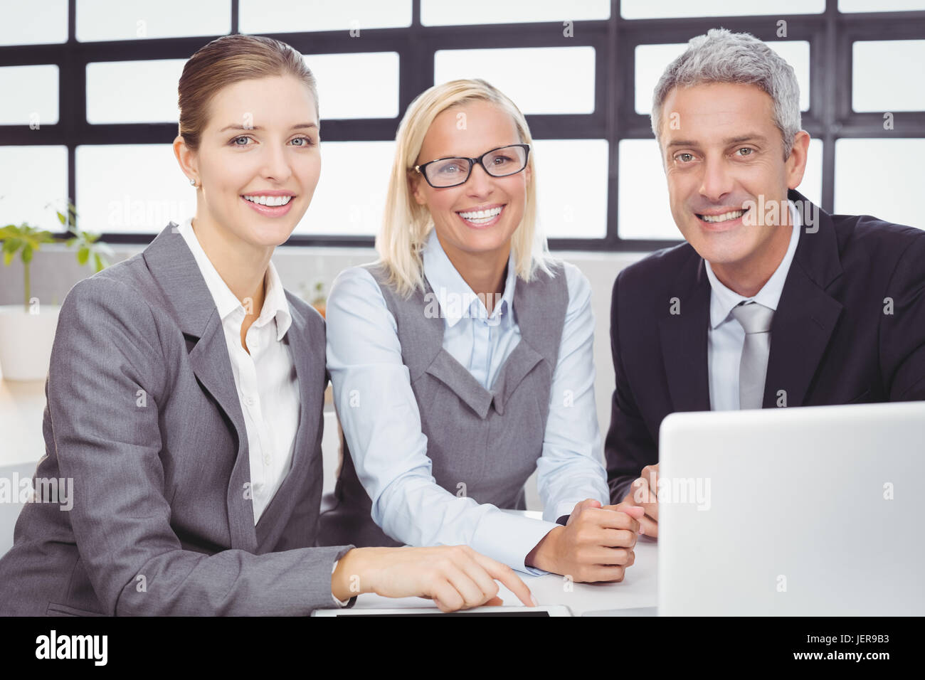 Happy business people with laptop at desk Stock Photo - Alamy