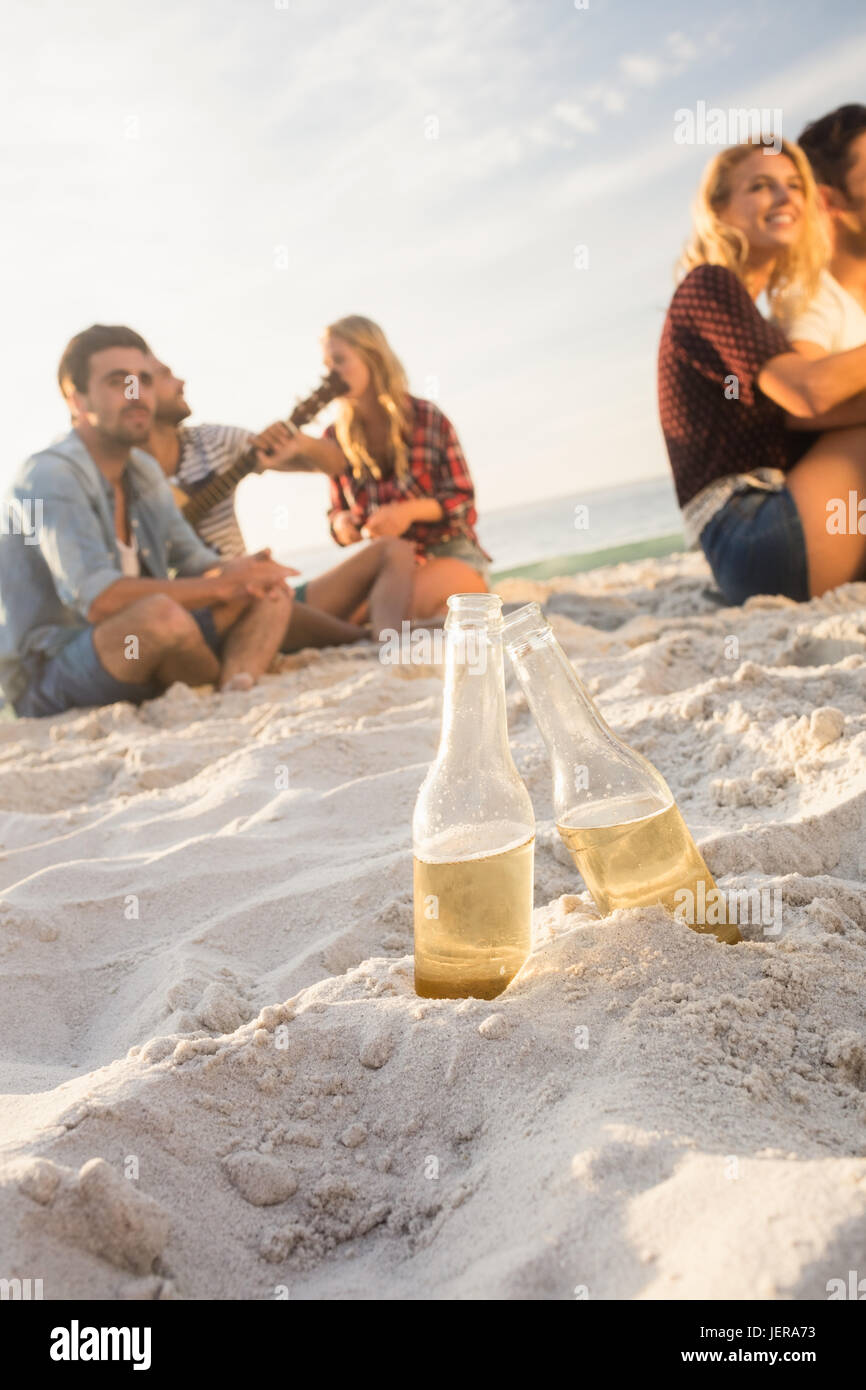 Smiling friends sitting on sand Stock Photo - Alamy
