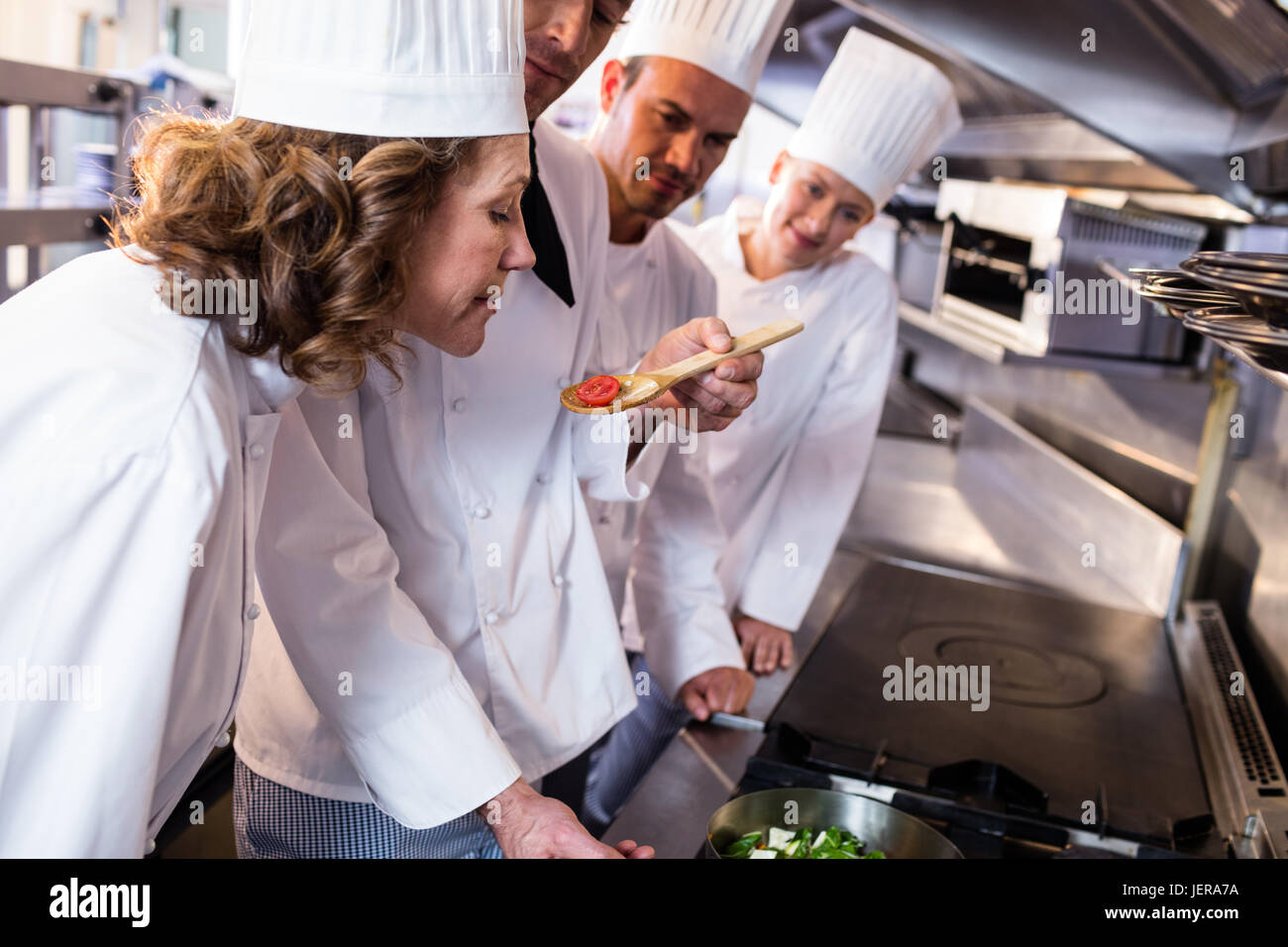Head chef showing food to his colleagues Stock Photo - Alamy
