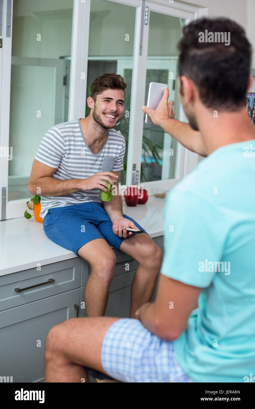 Man showing phone to smiling friend Stock Photo - Alamy