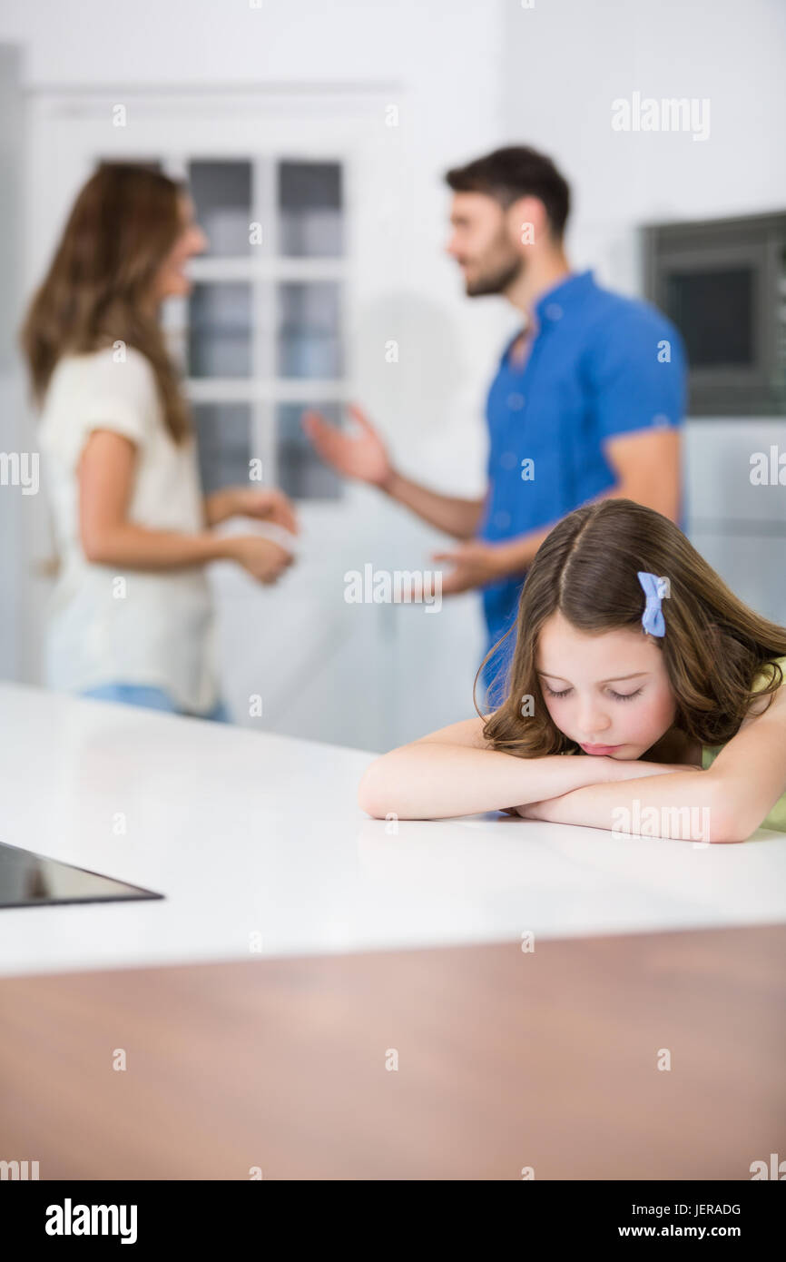 Upset girl leaning on table against parents Stock Photo - Alamy
