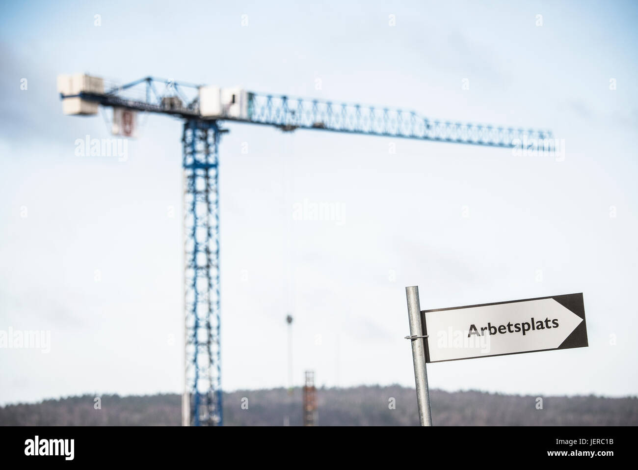 Directional sign, building crane on background Stock Photo - Alamy