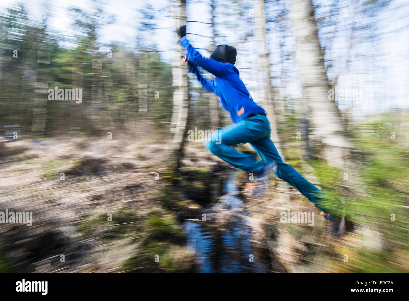 Boy jumping through stream Stock Photo - Alamy