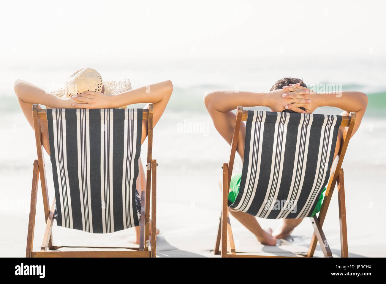Rear view of couple relaxing on the beach Stock Photo - Alamy