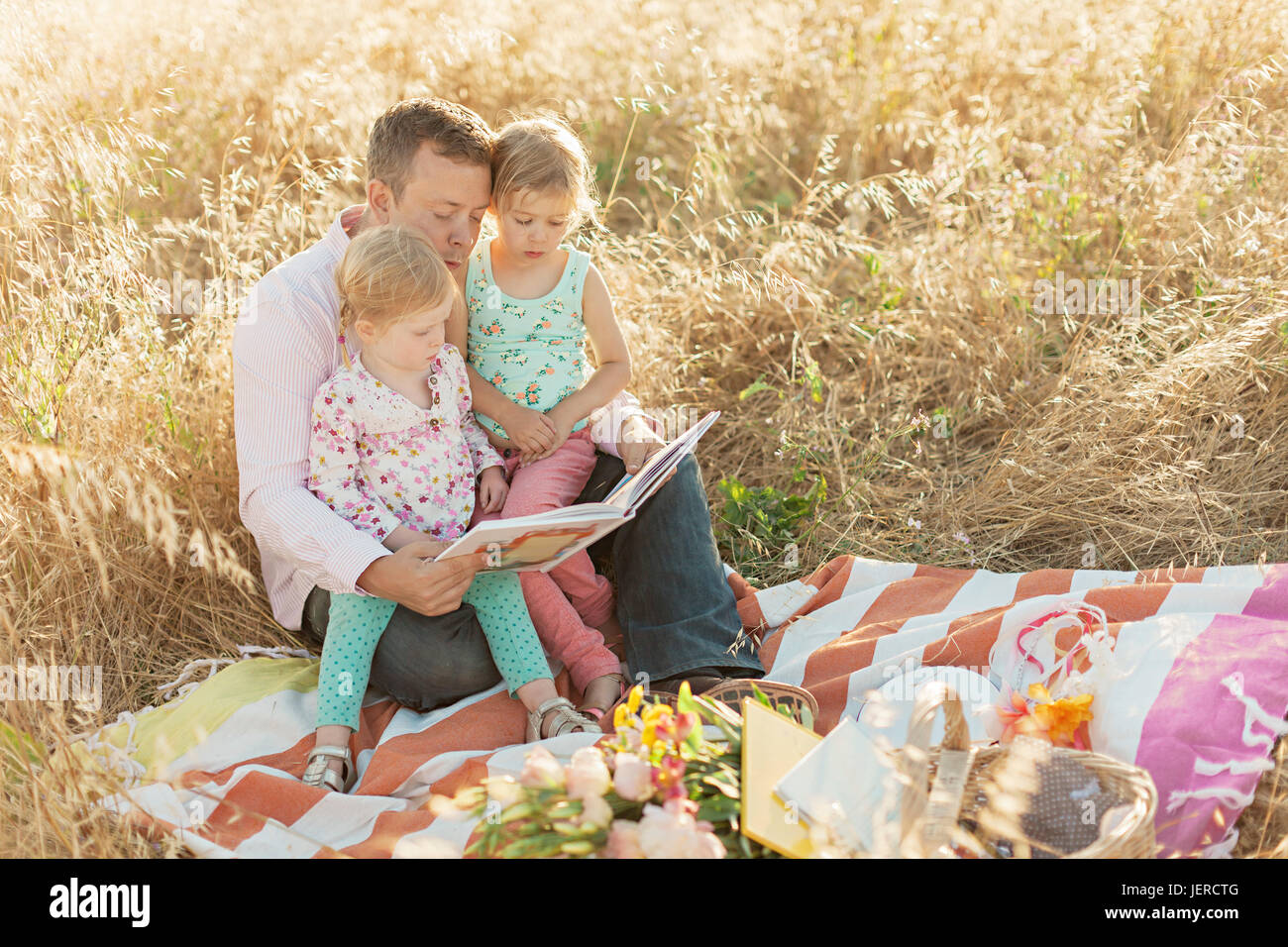 Father reading book to daughters Stock Photo - Alamy
