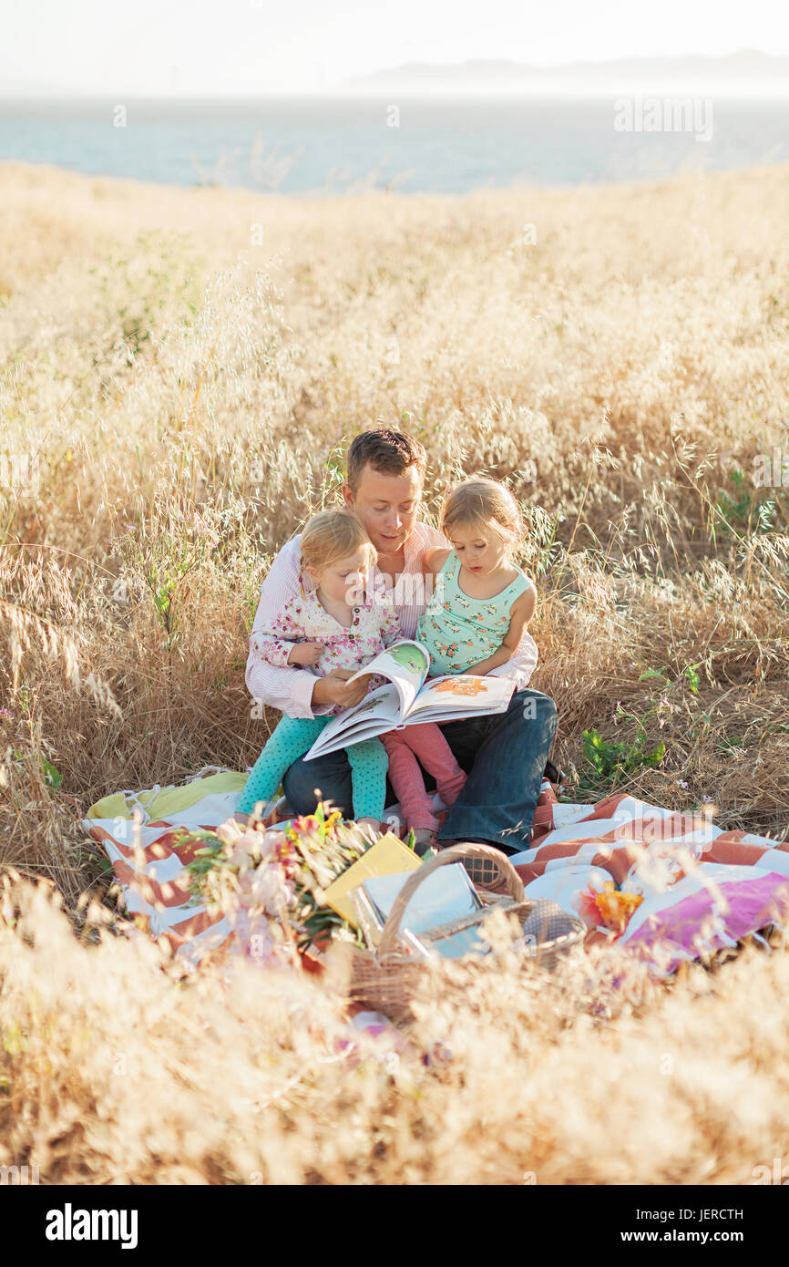 Father reading book to daughters Stock Photo - Alamy