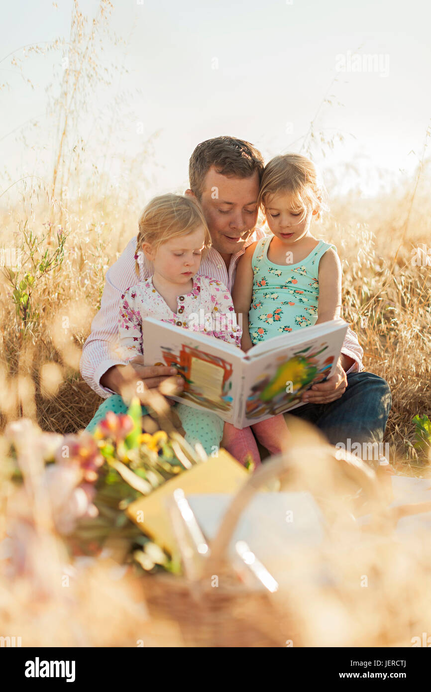 Father reading book to daughters Stock Photo - Alamy