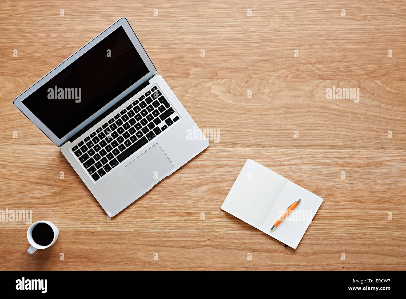 Laptop and notebook on wooden desk Stock Photo - Alamy