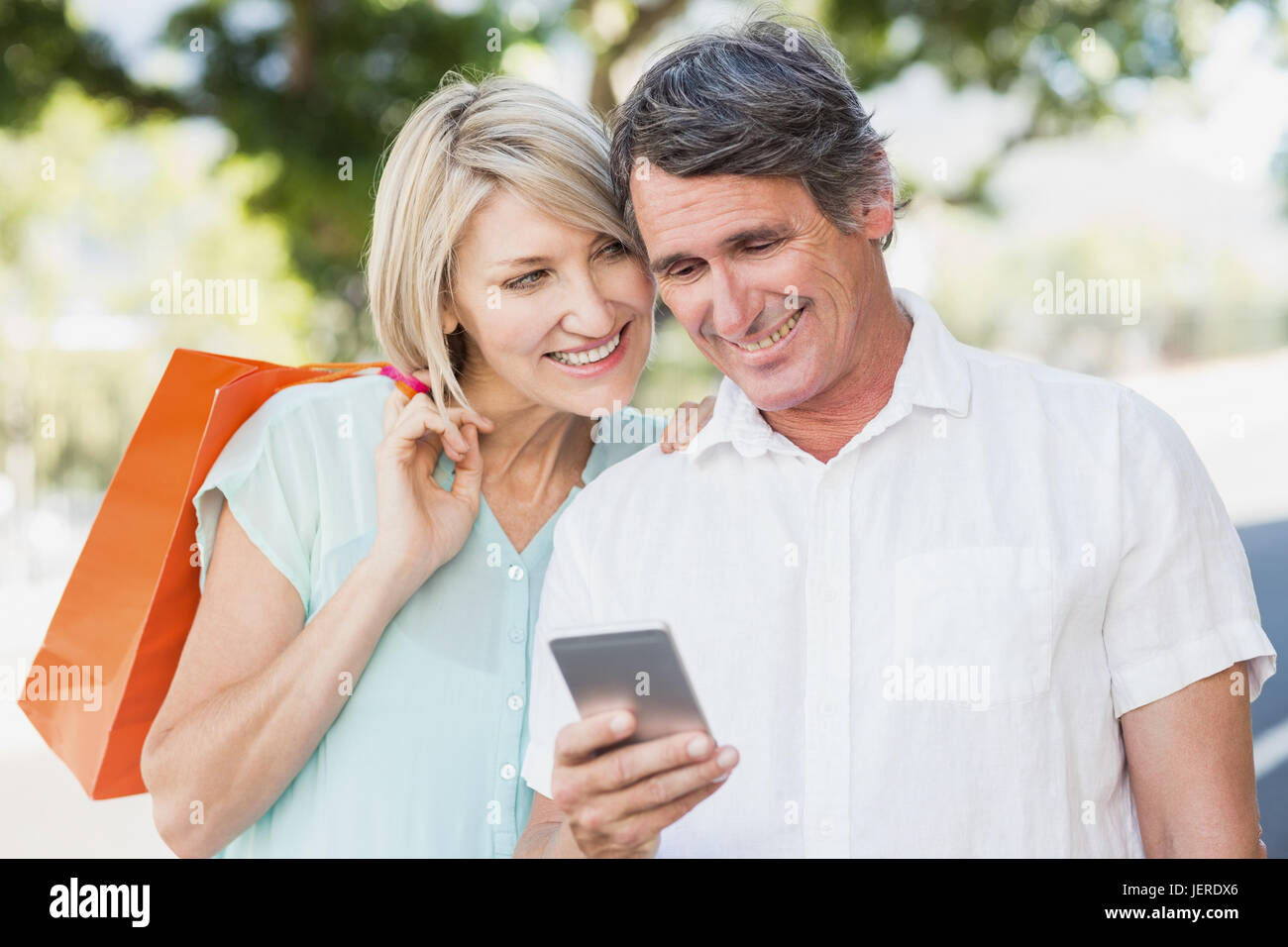 Couple using cellphone while smiling Stock Photo - Alamy