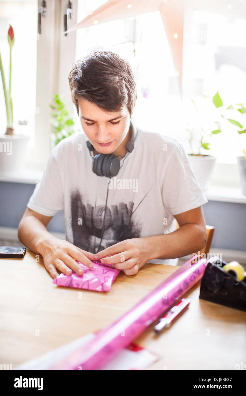 Teenage boy wrapping present Stock Photo - Alamy