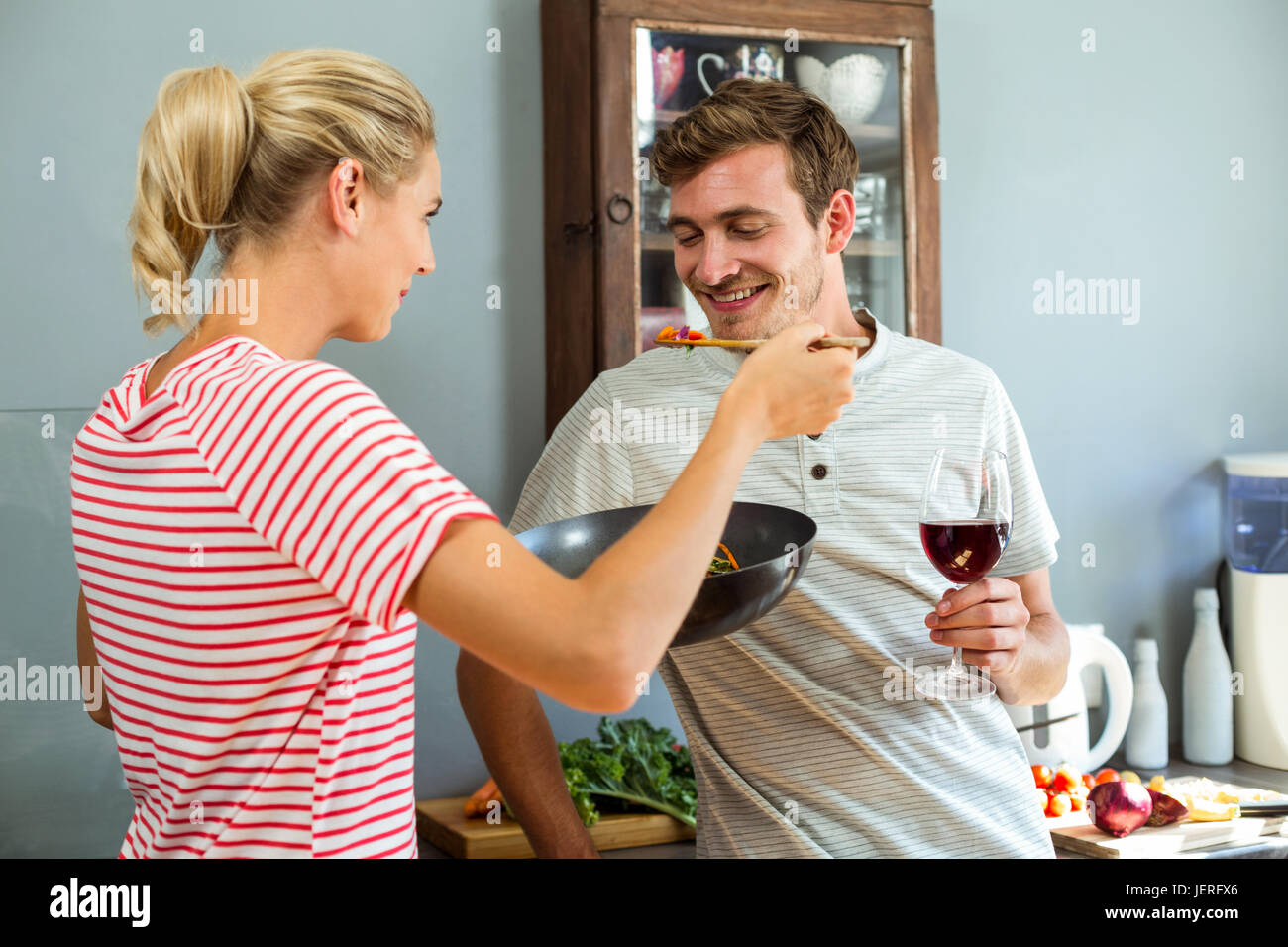 Wife cooking food with husband in kitchen Stock Photo - Alamy