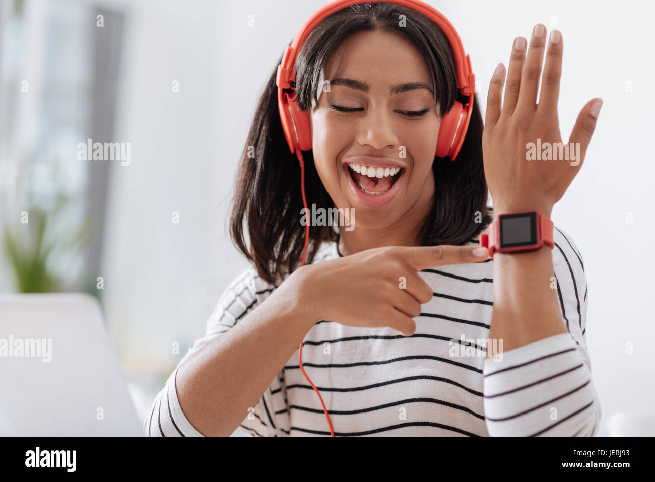 Happy young woman pointing at her watch Stock Photo - Alamy