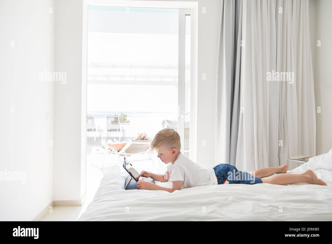 Boy on bed using digital tablet Stock Photo - Alamy