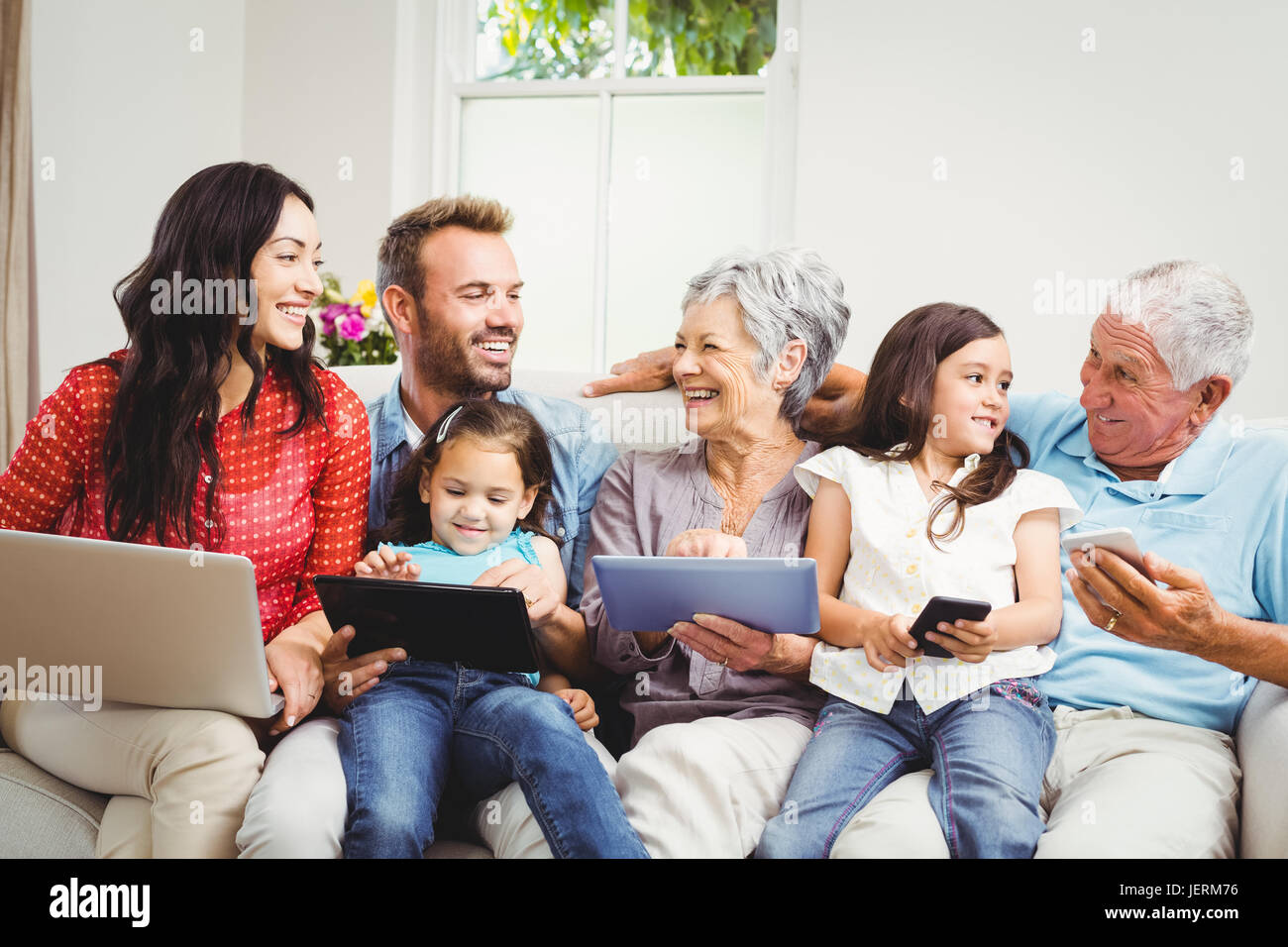 Family smiling while holding technologies Stock Photo - Alamy