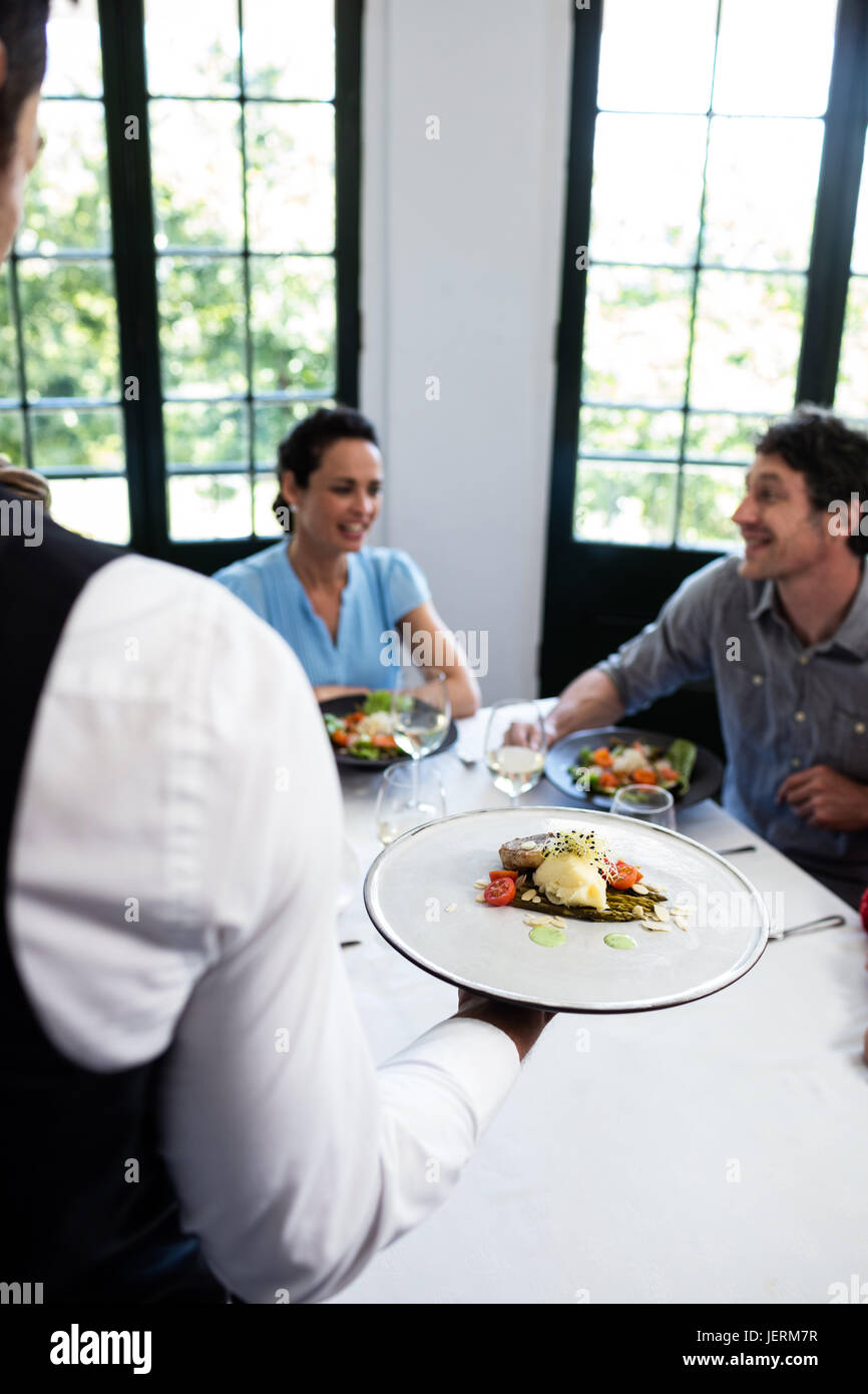 Waiter serving meal to customers Stock Photo - Alamy