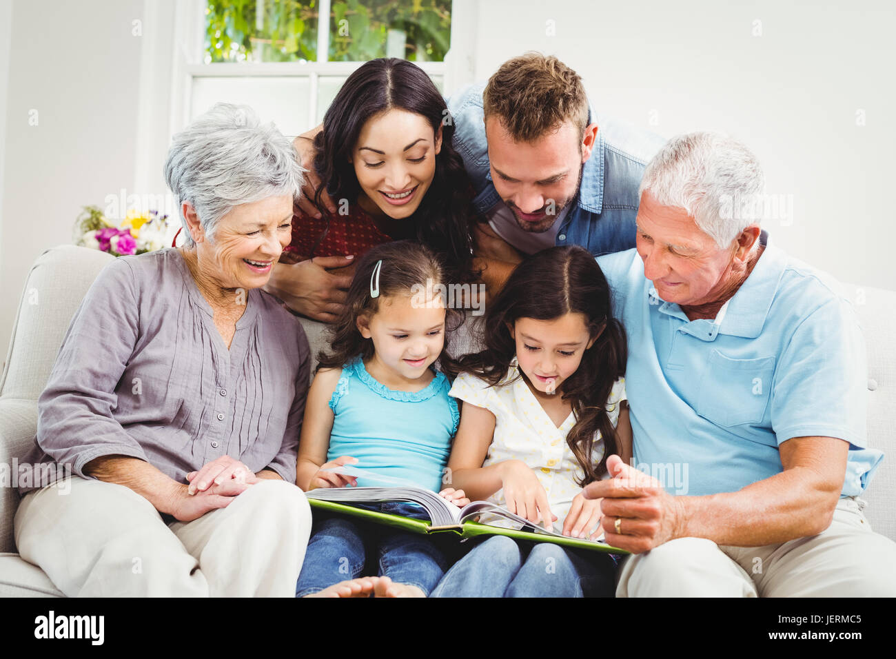 Family assisting girls while reading book Stock Photo - Alamy