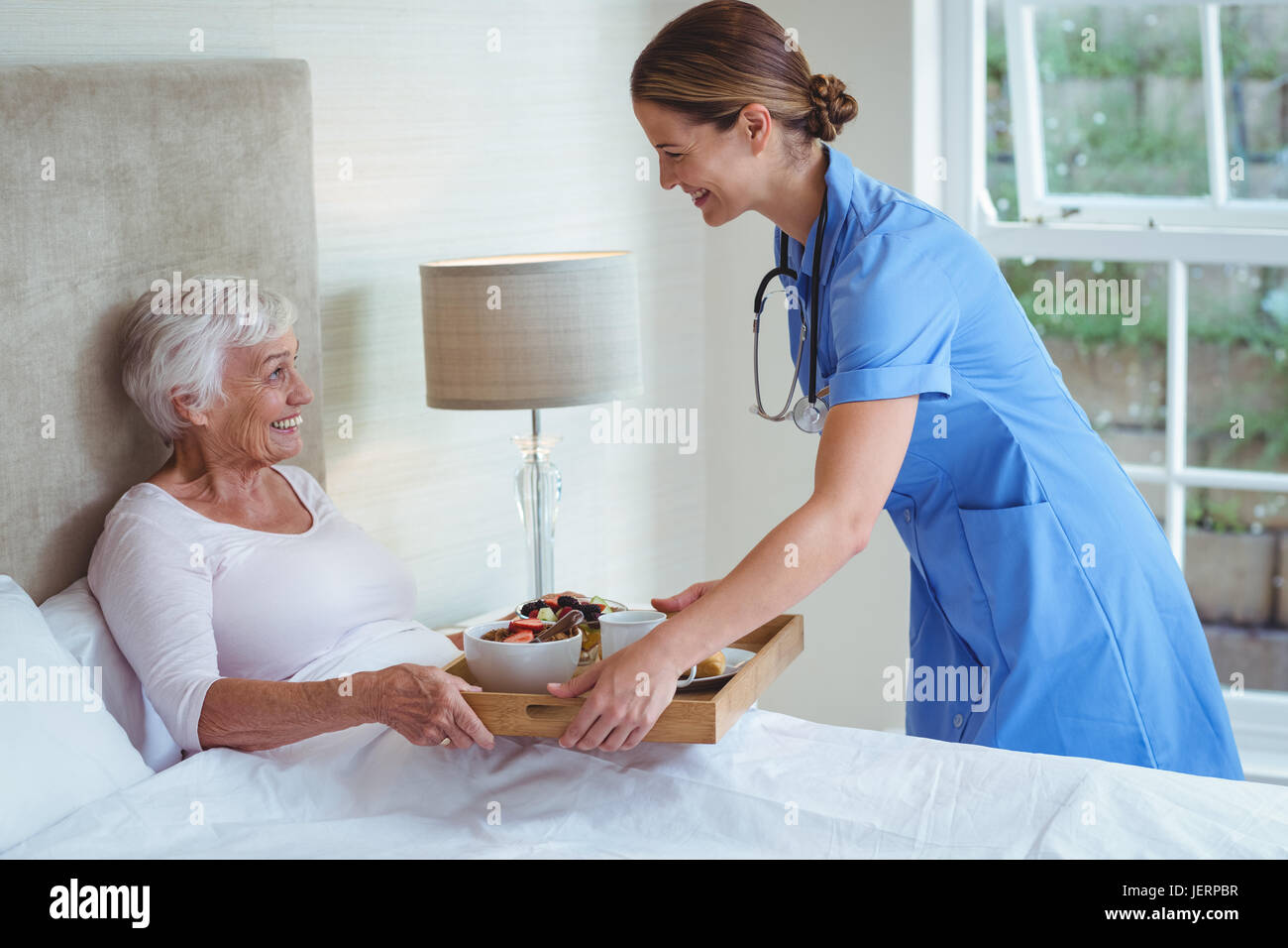 Smiling nurse giving food to senior woman Stock Photo - Alamy