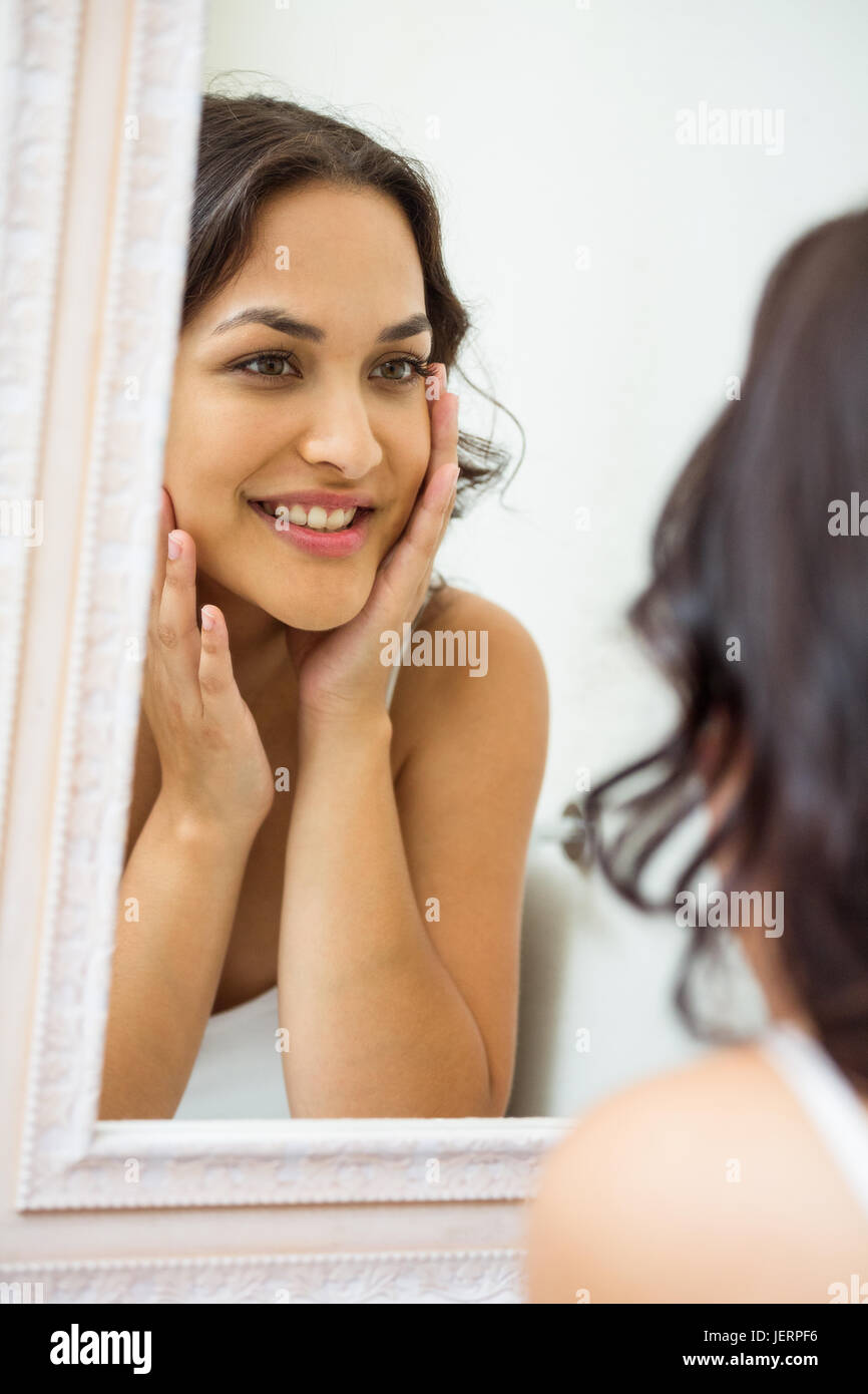 Young woman looking in mirror of bathroom Stock Photo - Alamy