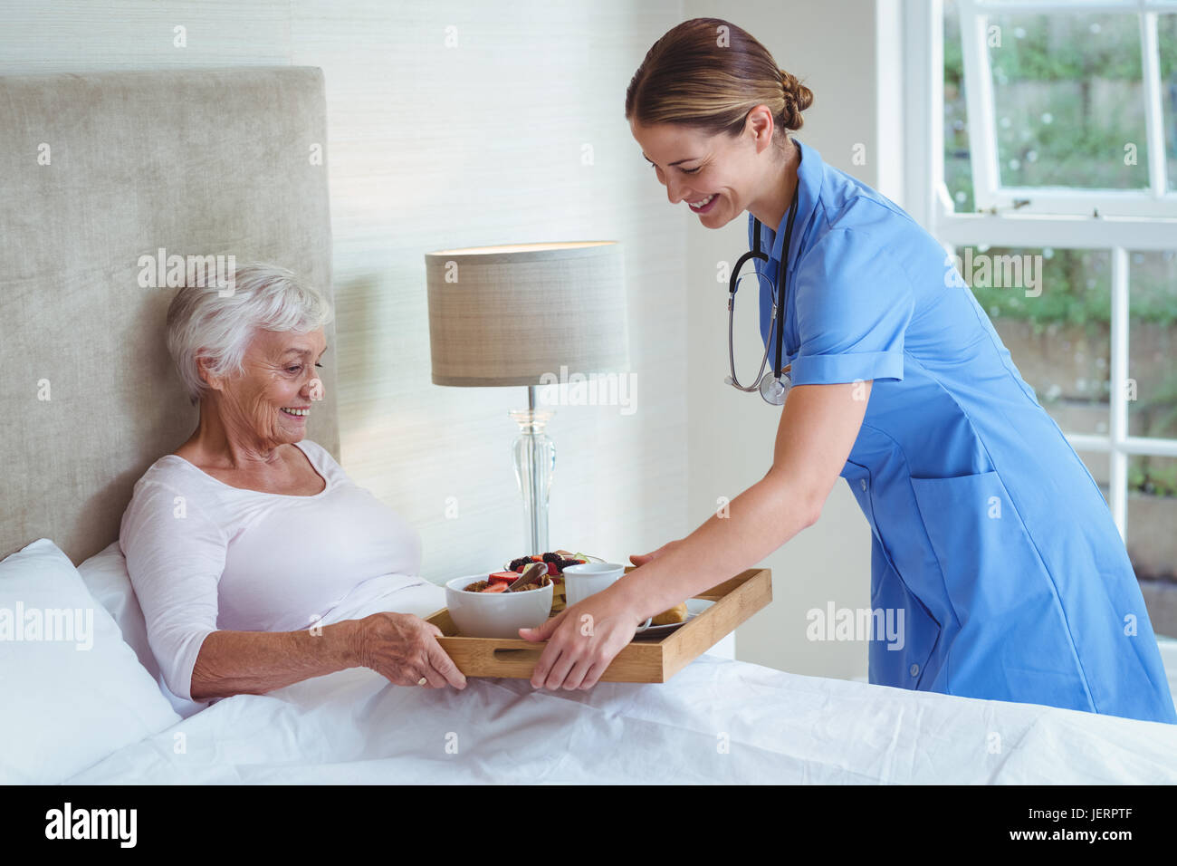Happy nurse giving food to senior woman Stock Photo - Alamy