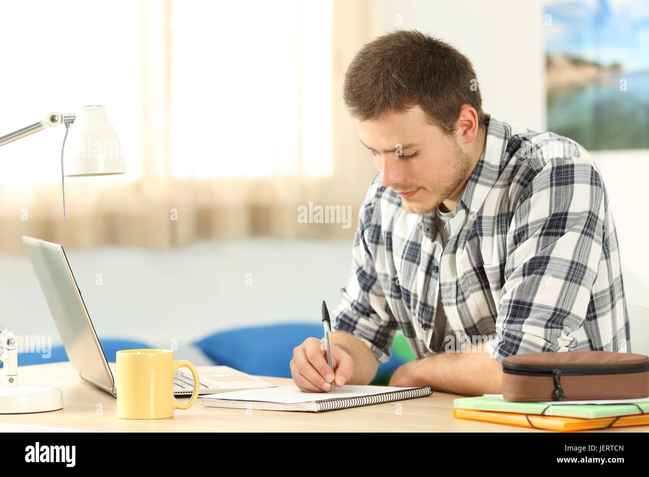 Portrait of a student writing in a notebook doing homework in a desk in ...