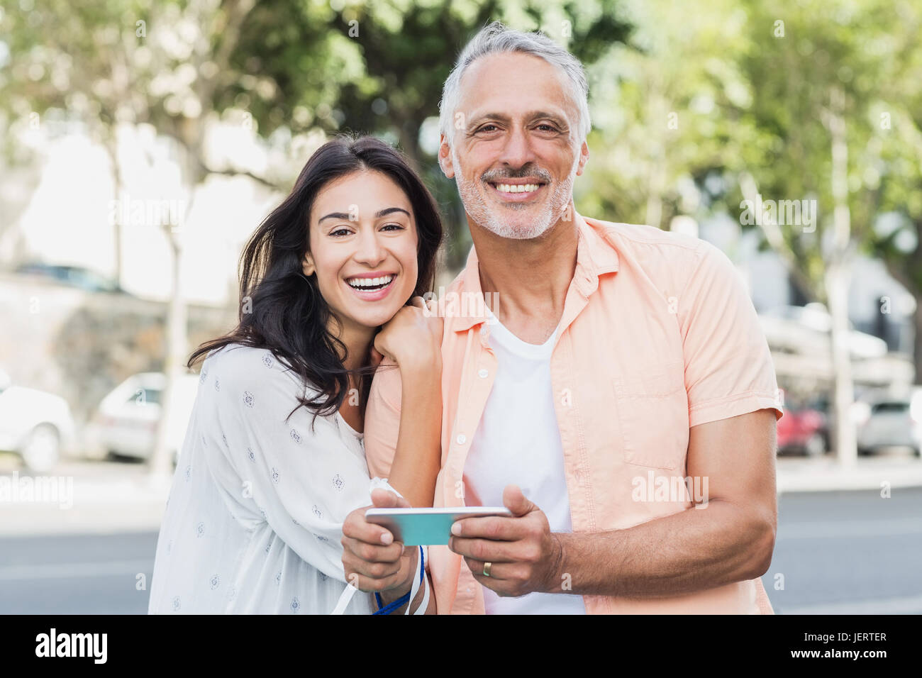 Cheerful couple using phone Stock Photo - Alamy