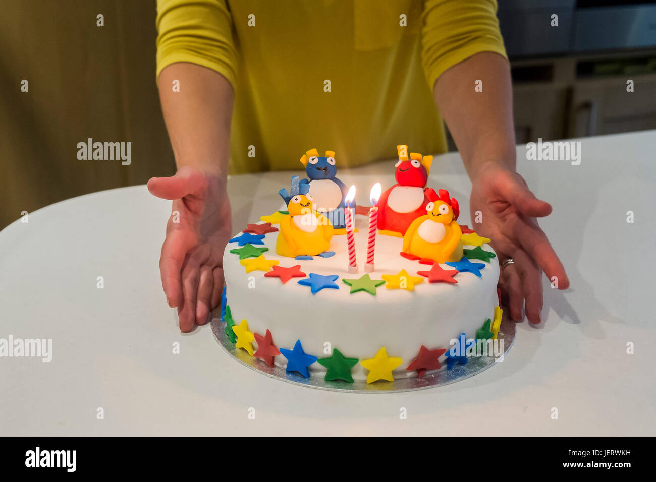 A colourful birthday cake with two lit candles Stock Photo - Alamy