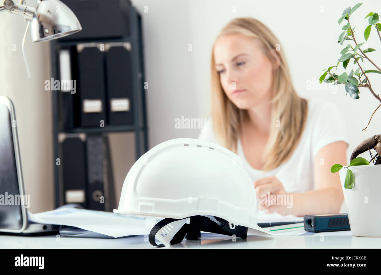 Architect's white helmet in the central point and a woman architect in ...