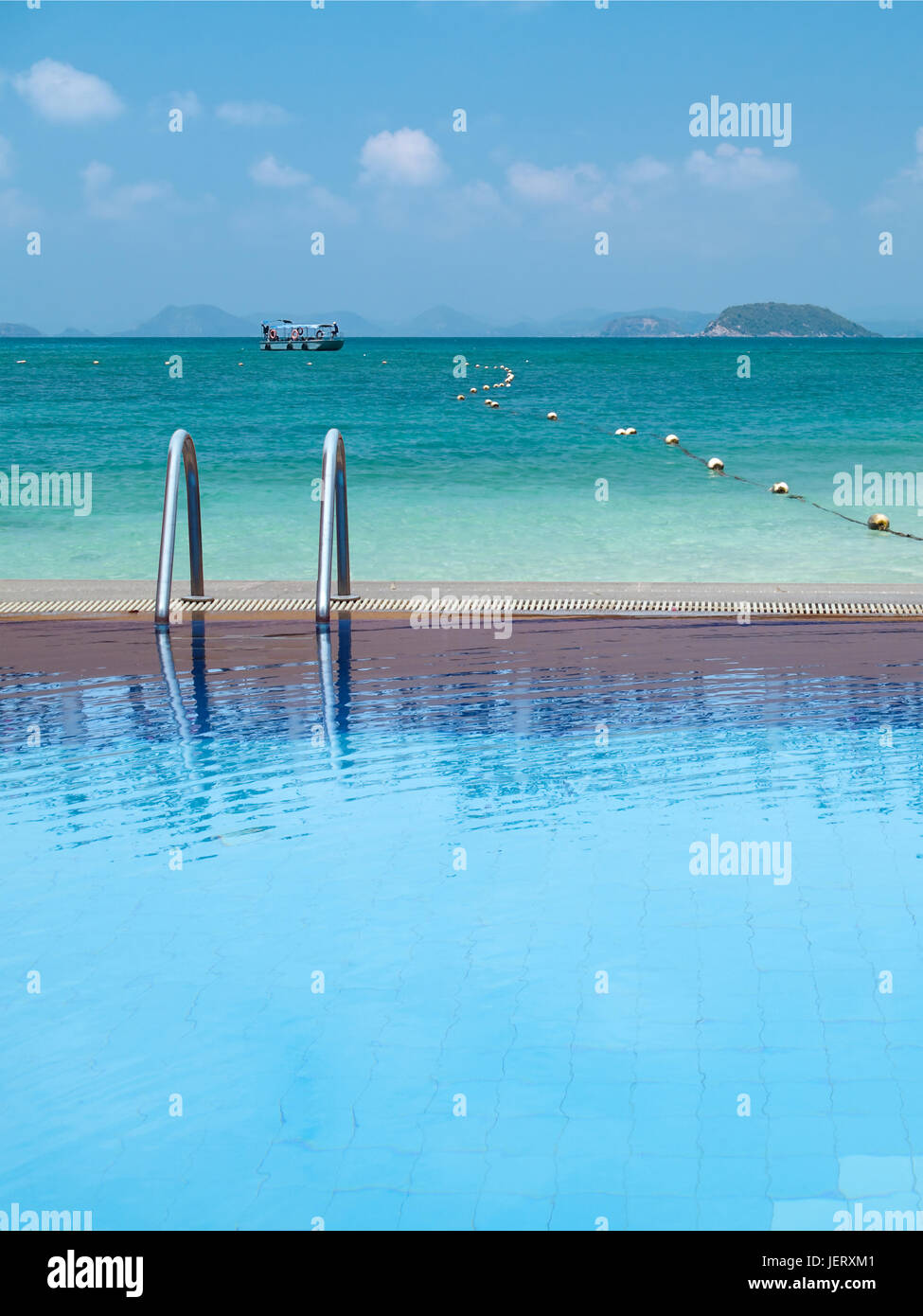 Outdoor swimming pool with emerald sea and boat Stock Photo - Alamy
