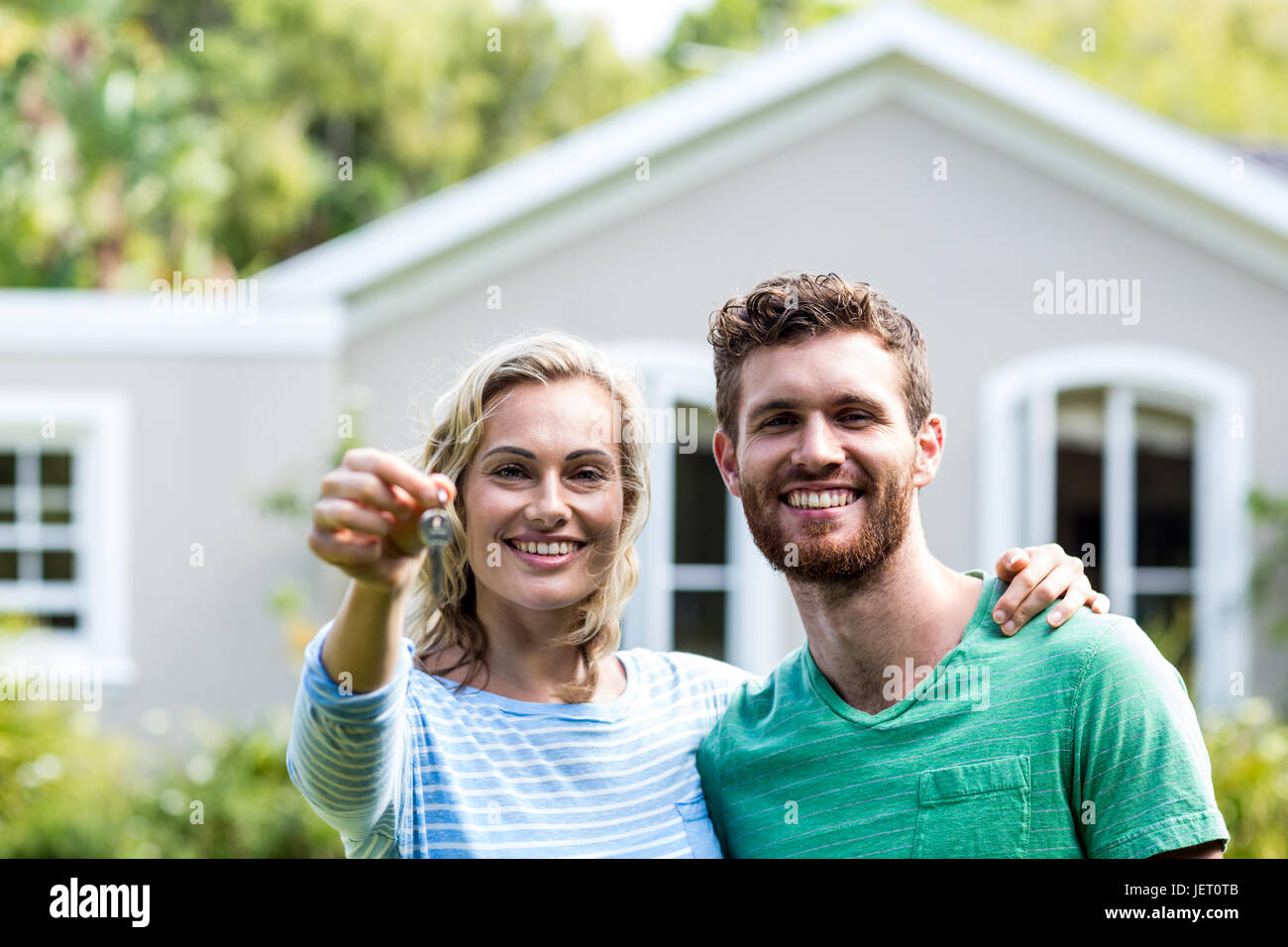 Couple with keys standing against house Stock Photo - Alamy